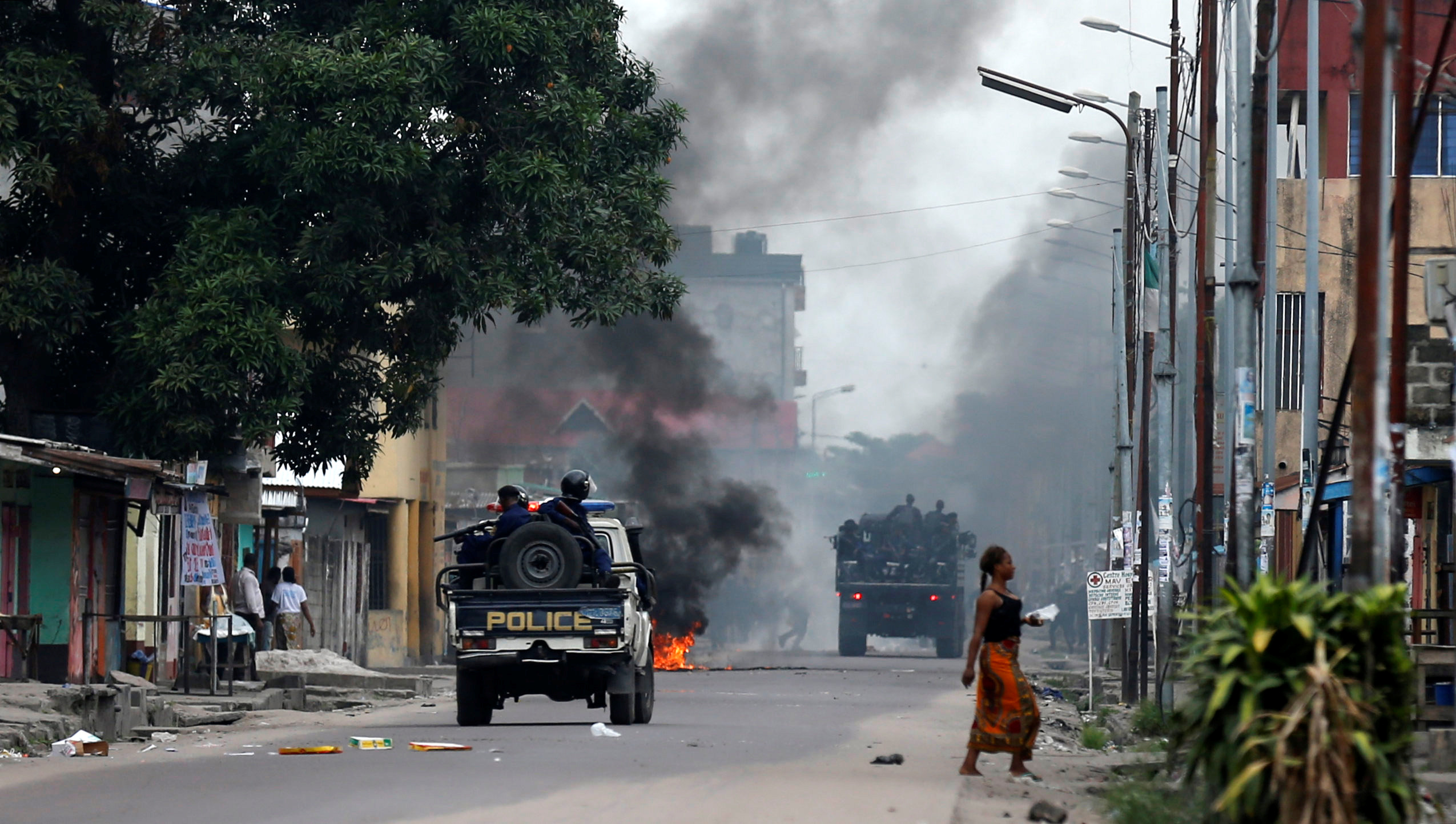 Congolese policemen drive past a fire barricade during demonstrations ...